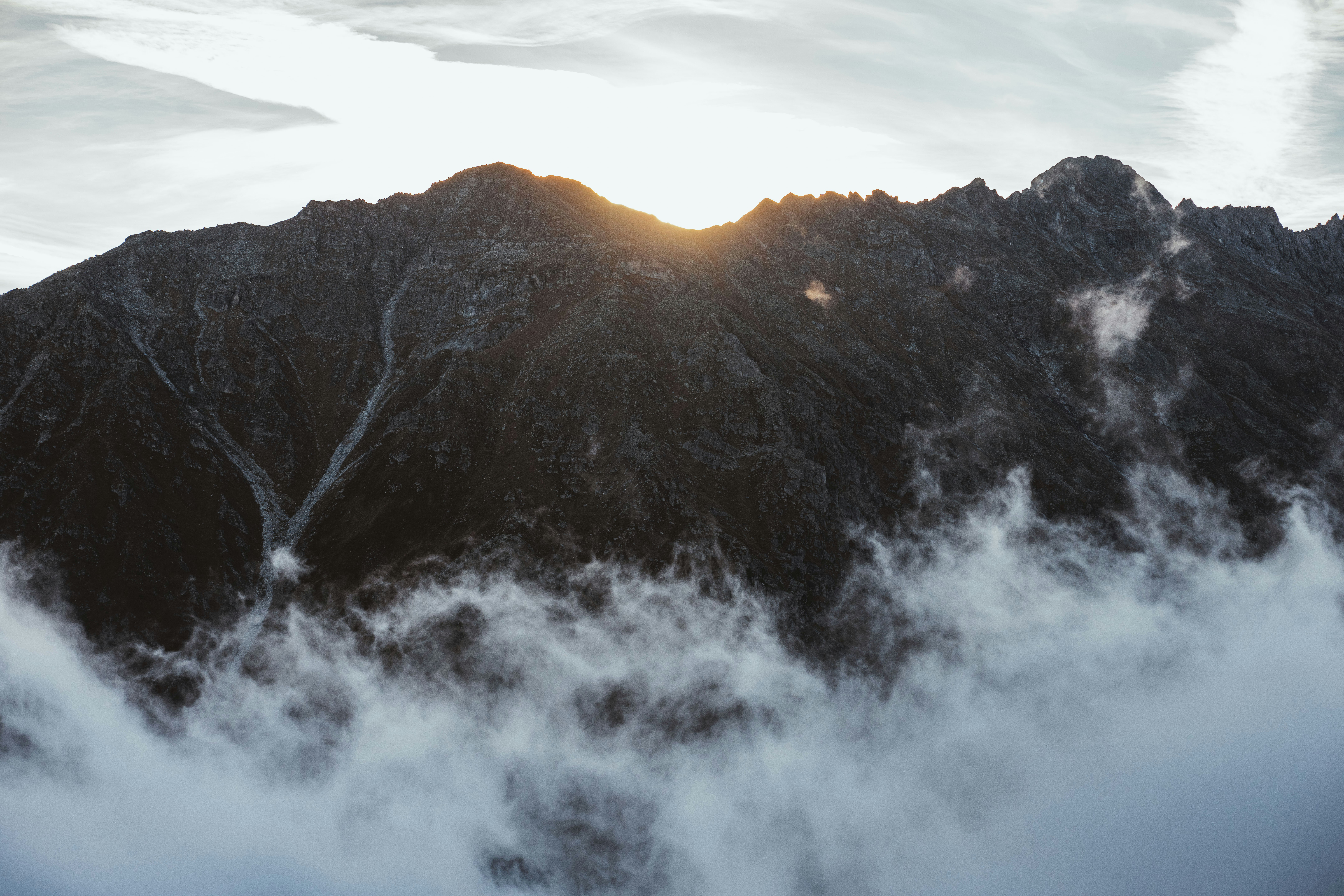 First Light above the Crest: A Mountain Peak Emerging from the Clouds