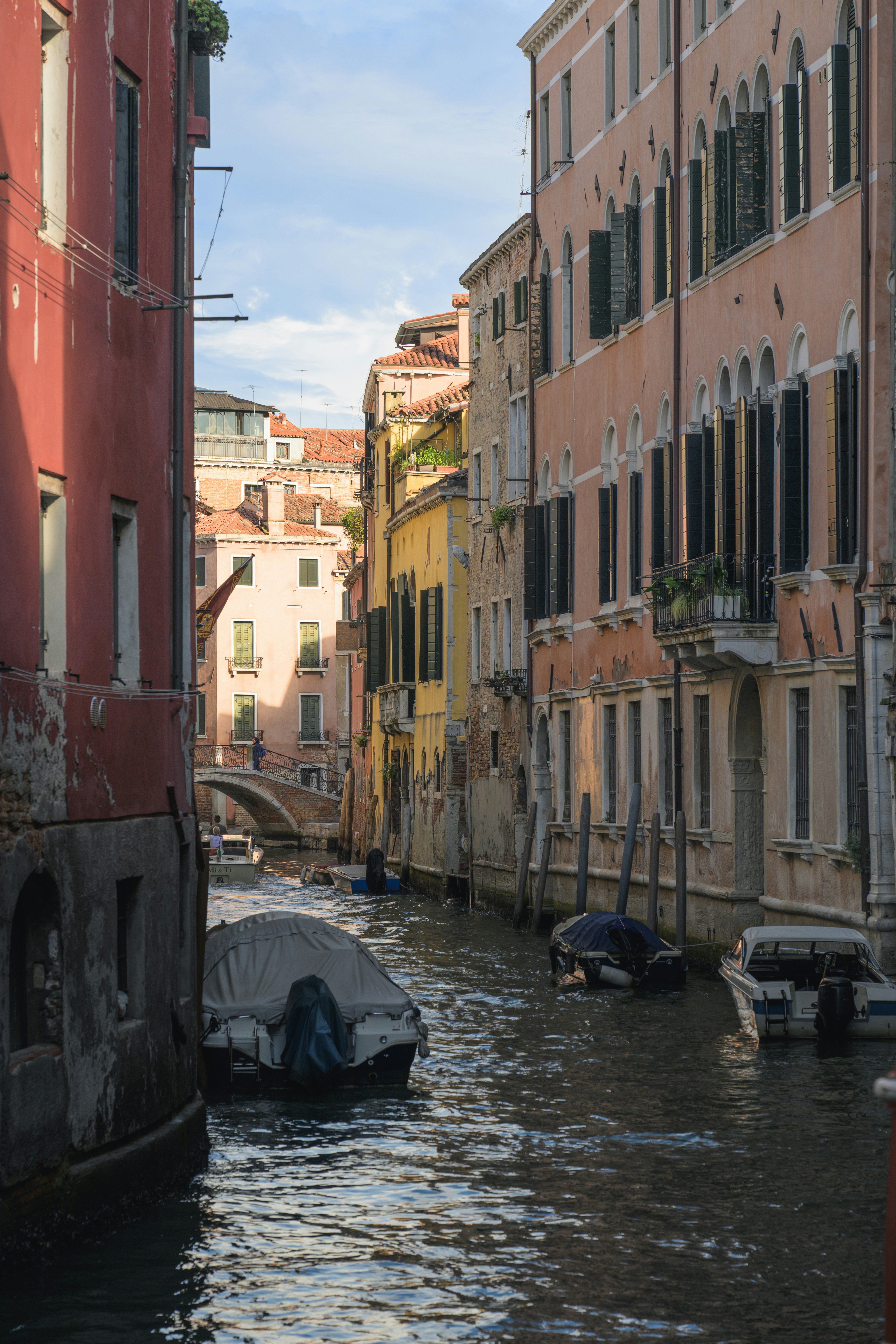 Sunlit Canal Corridor Between Painted Facades