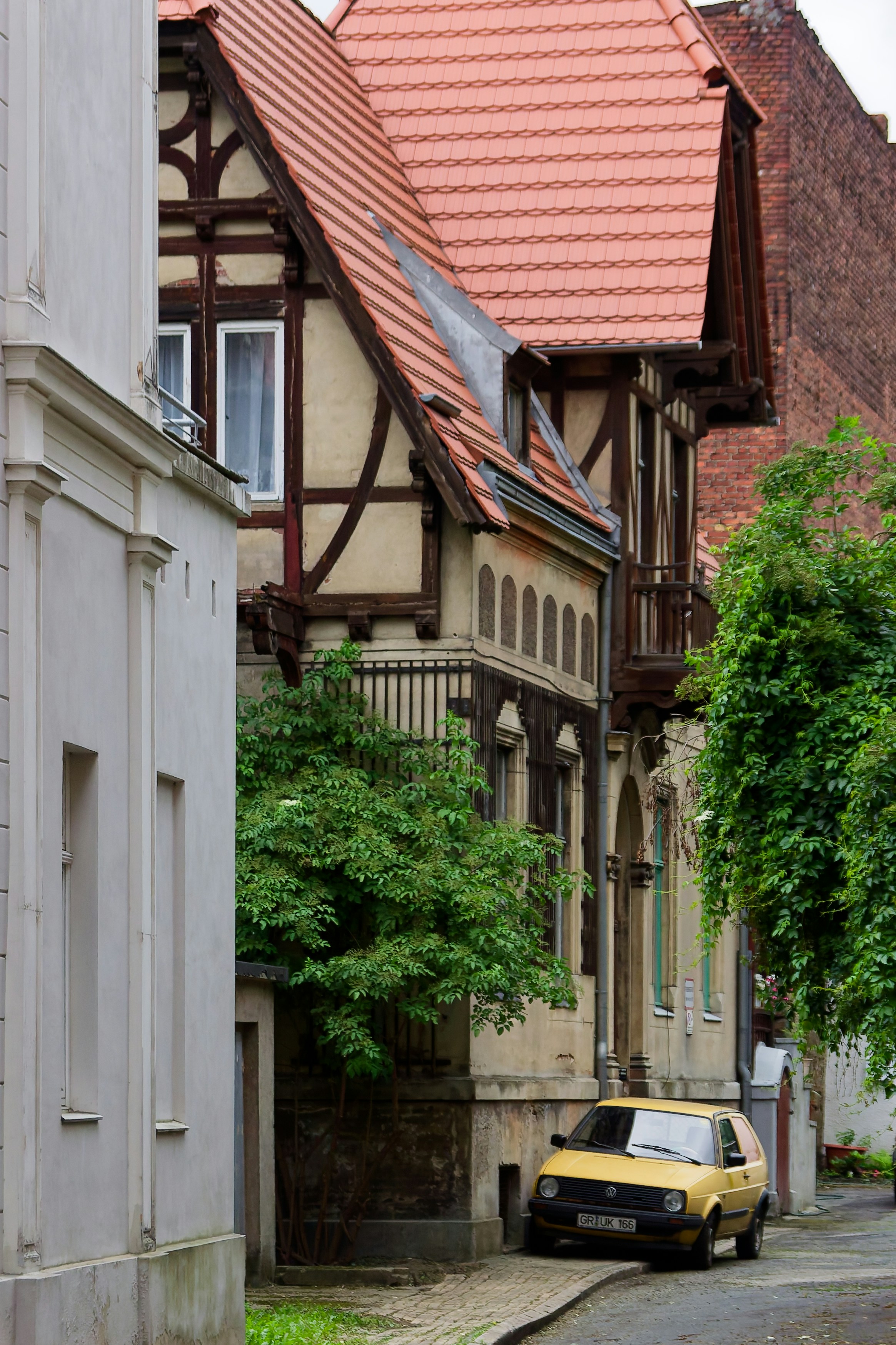 A vintage yellow Volkswagen Golf parked on a quiet street beside historic half-timbered architecture in Görlitz, Germany.
