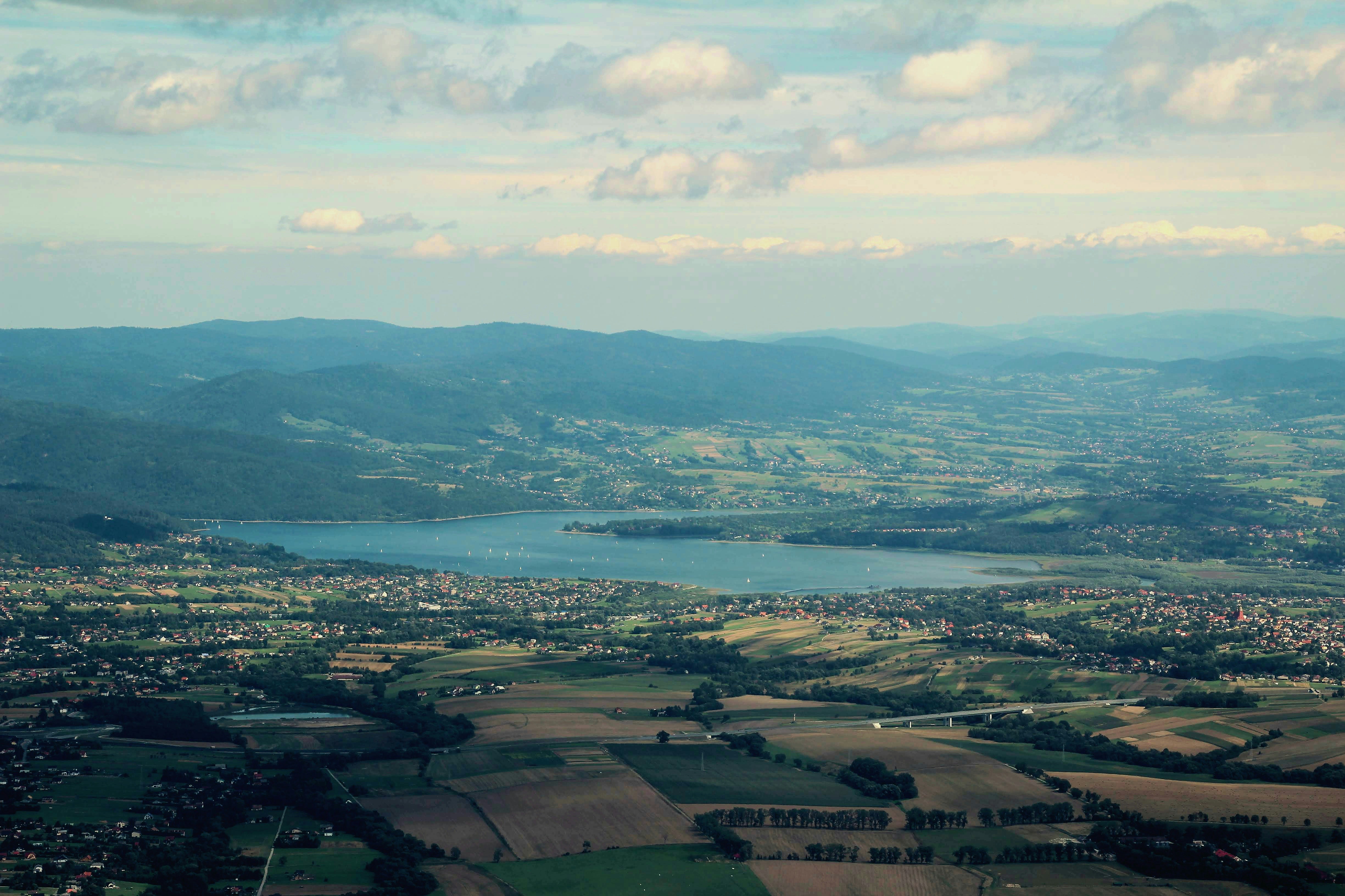 Wide valley with a lake and patchwork fields beneath a layered mountain range.