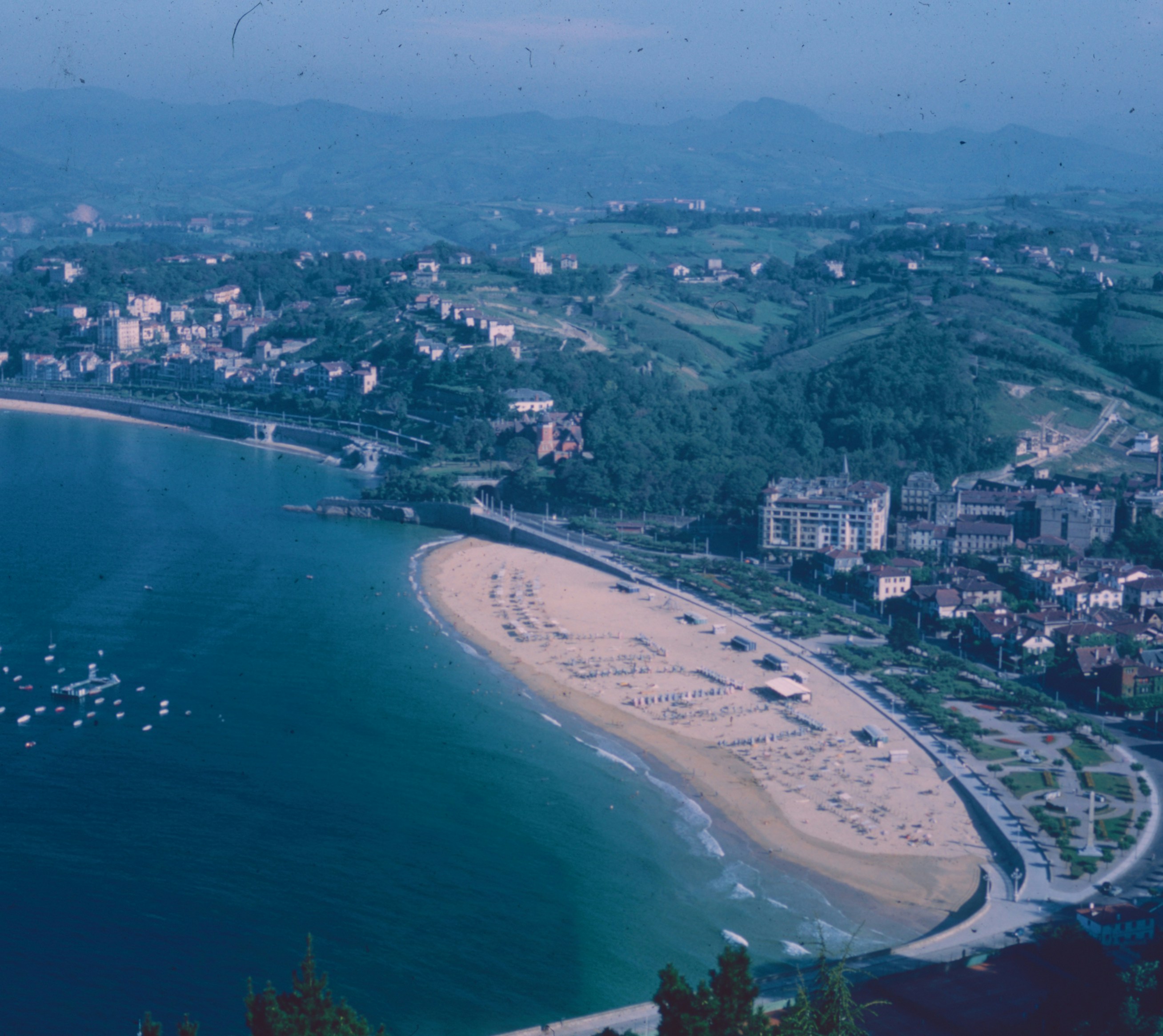 Aerial Calm: Beachfront Village Lined by Hills Under a Blue Dusk