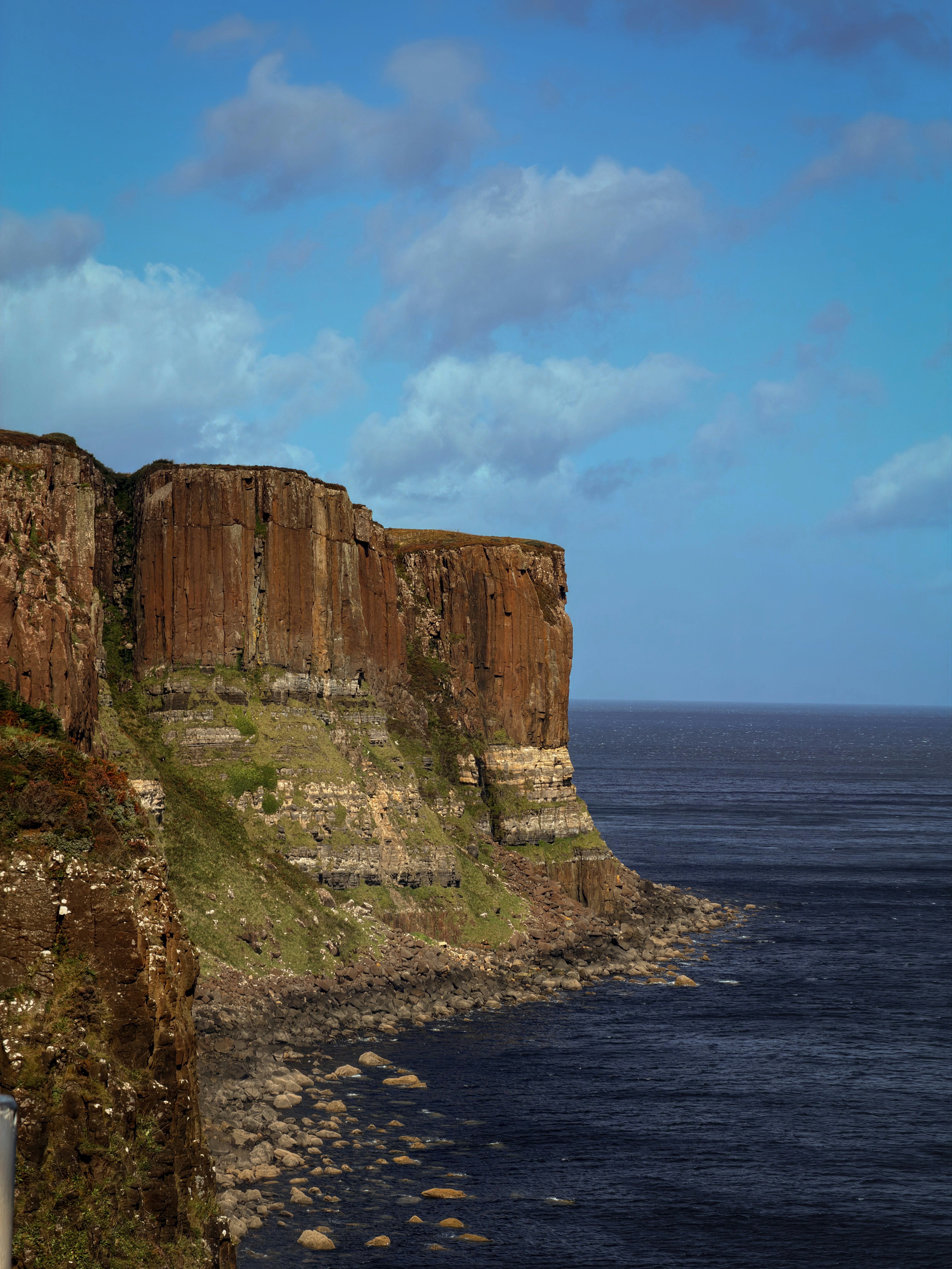 Cliffside Peninsula: Weathered Red Dolerite Faces Against Atlantic Blues