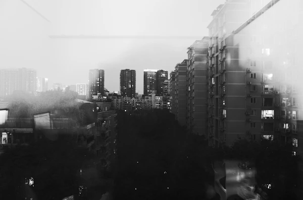 window shot of urban flats | grayscale photo of city buildings