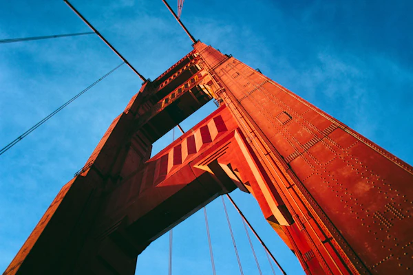 Upward view of the Golden Gate Bridge's iconic red structure against a vibrant blue sky.
